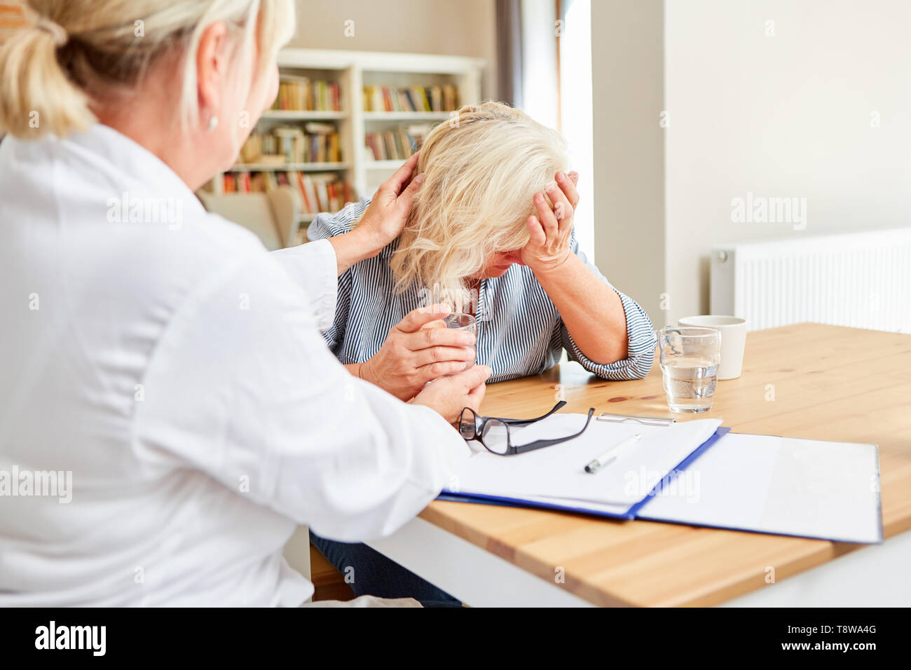 Crying senior patient is comforted by female doctor or nursing wife ...