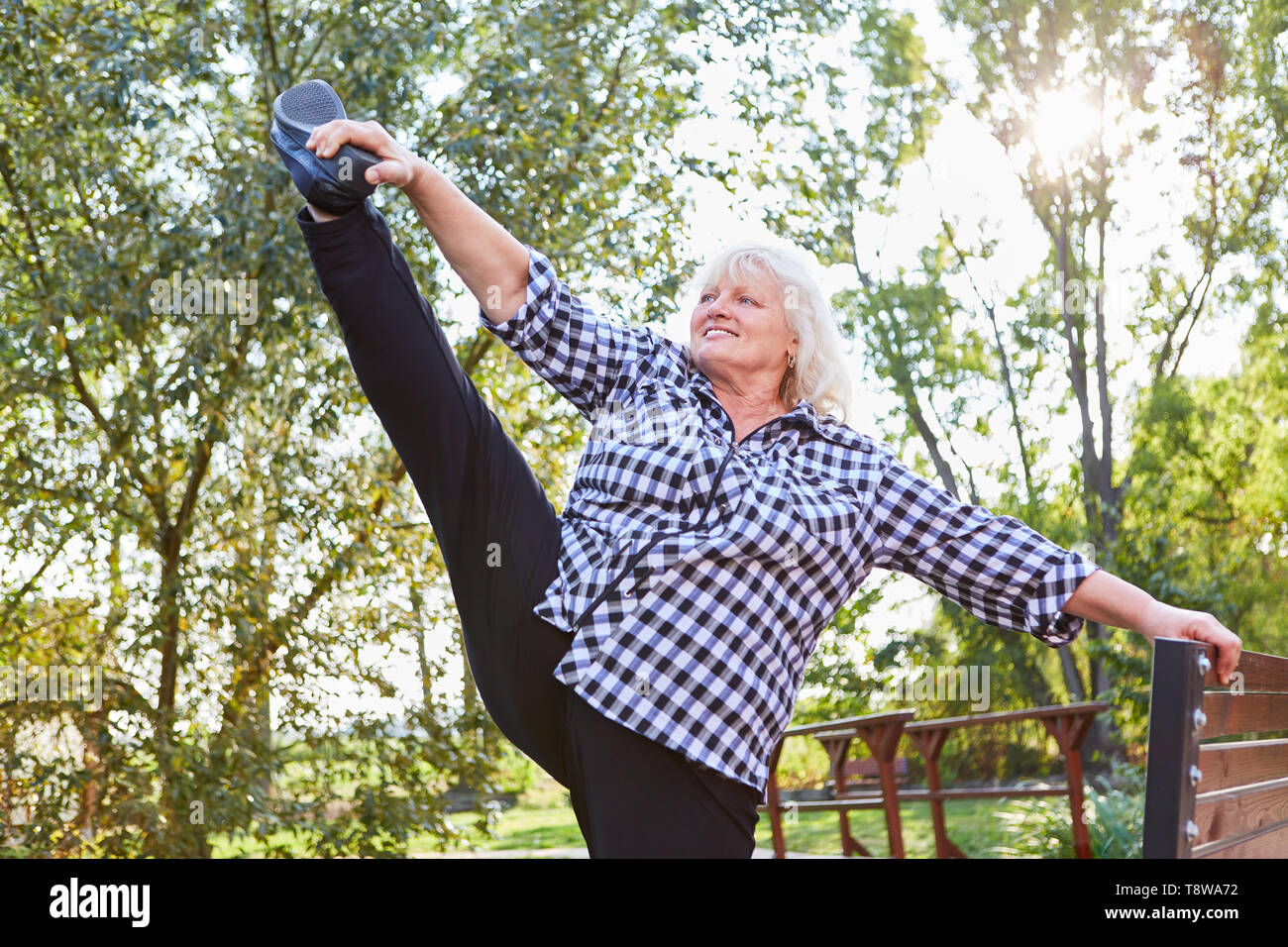 Vital senior woman stretching on one leg for flexibility and balance ...