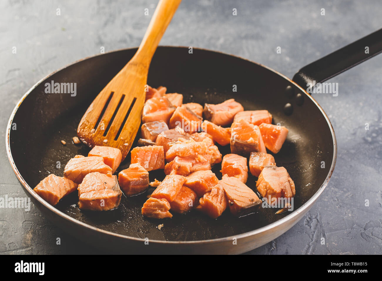 Diced salmon slices are fried in frying pan for pasta with creamy ...