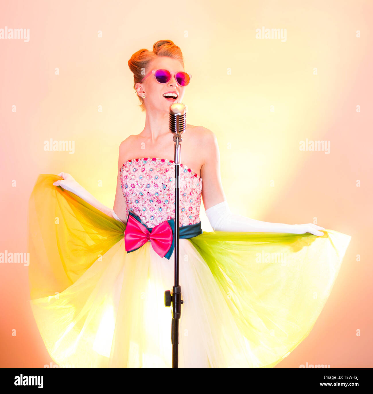 Happy girl singer in pink glasses smiles, flirts, enjoys life, dances ...