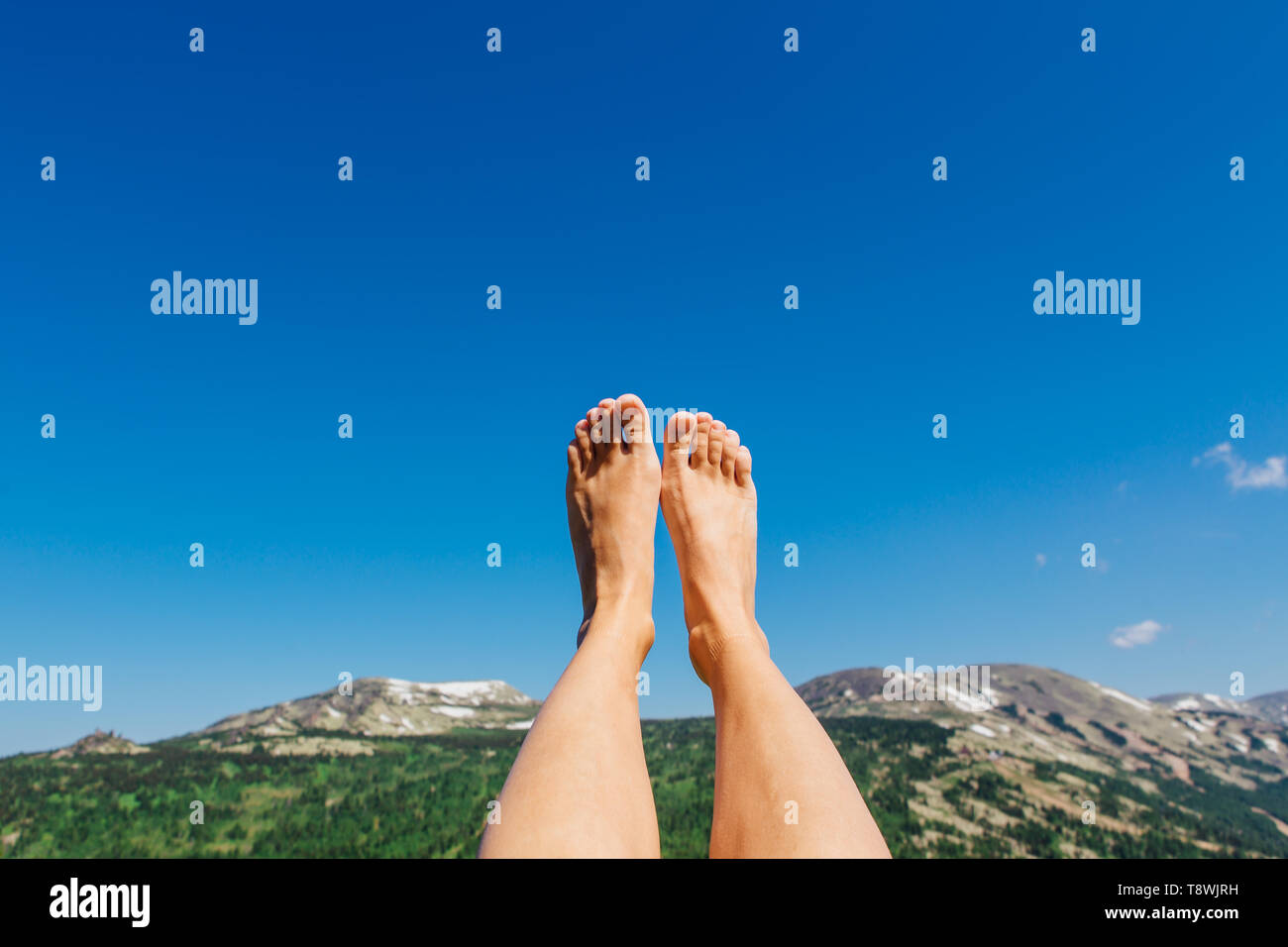 Female feet up infront of the clear blue sky and mountains Stock Photo ...