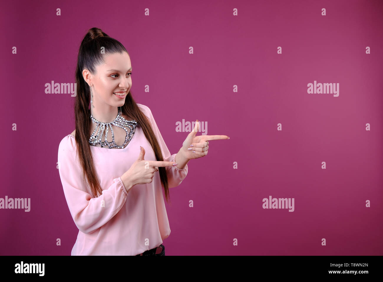 Smiling woman pointing finger side. portrait on pink background Stock ...