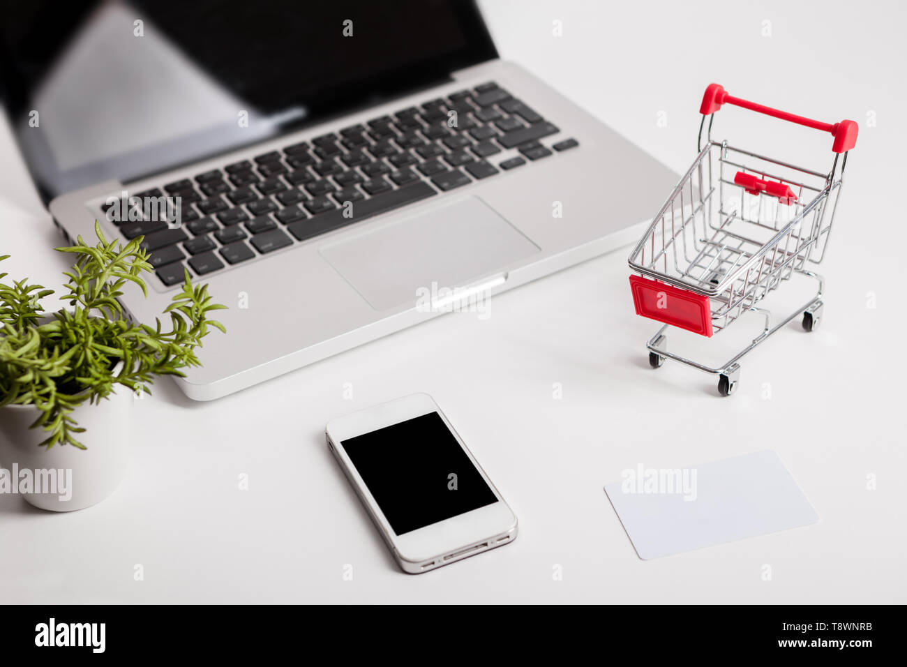 Online shopping. Bank card nearby a laptop and mini shopping cart on ...