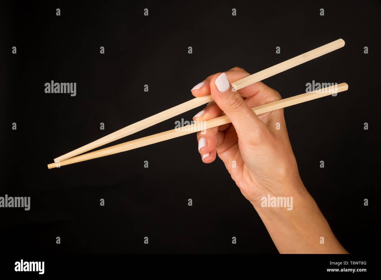 Female hand holding a set of chopsticks against black background Stock ...