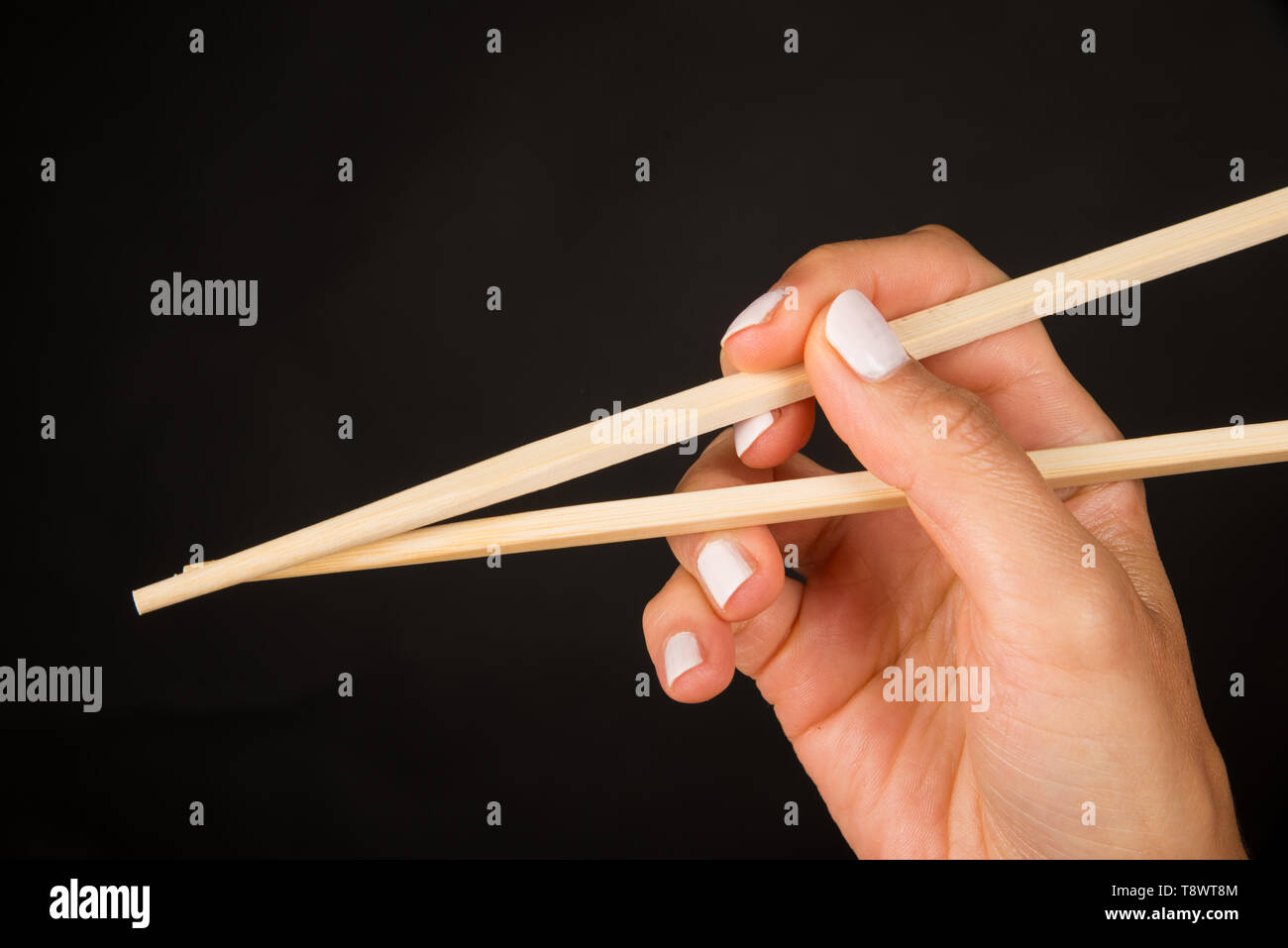 Female hand holding a set of chopsticks against black background Stock ...
