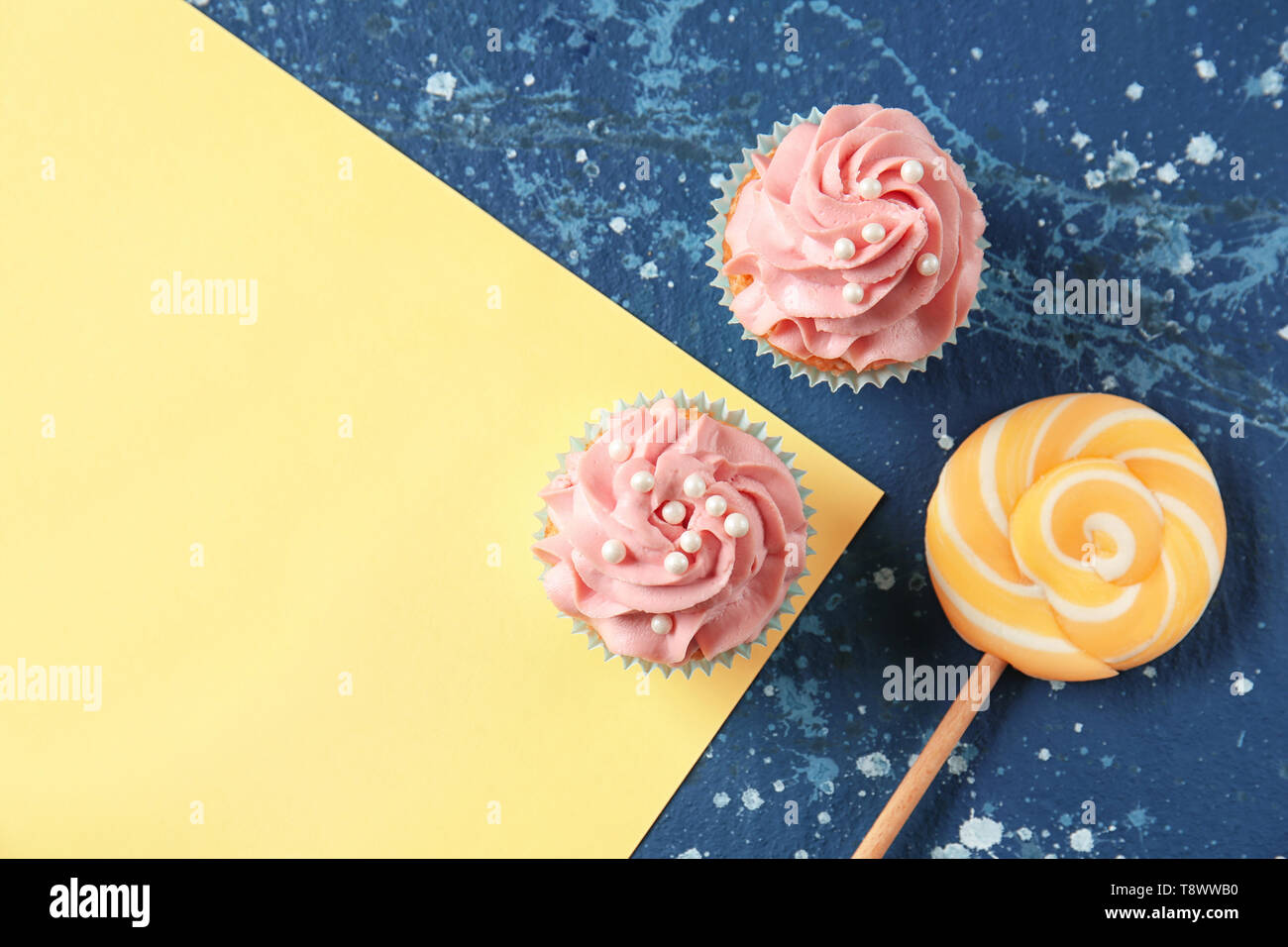 Delicious cupcakes with lollipop on color table Stock Photo - Alamy