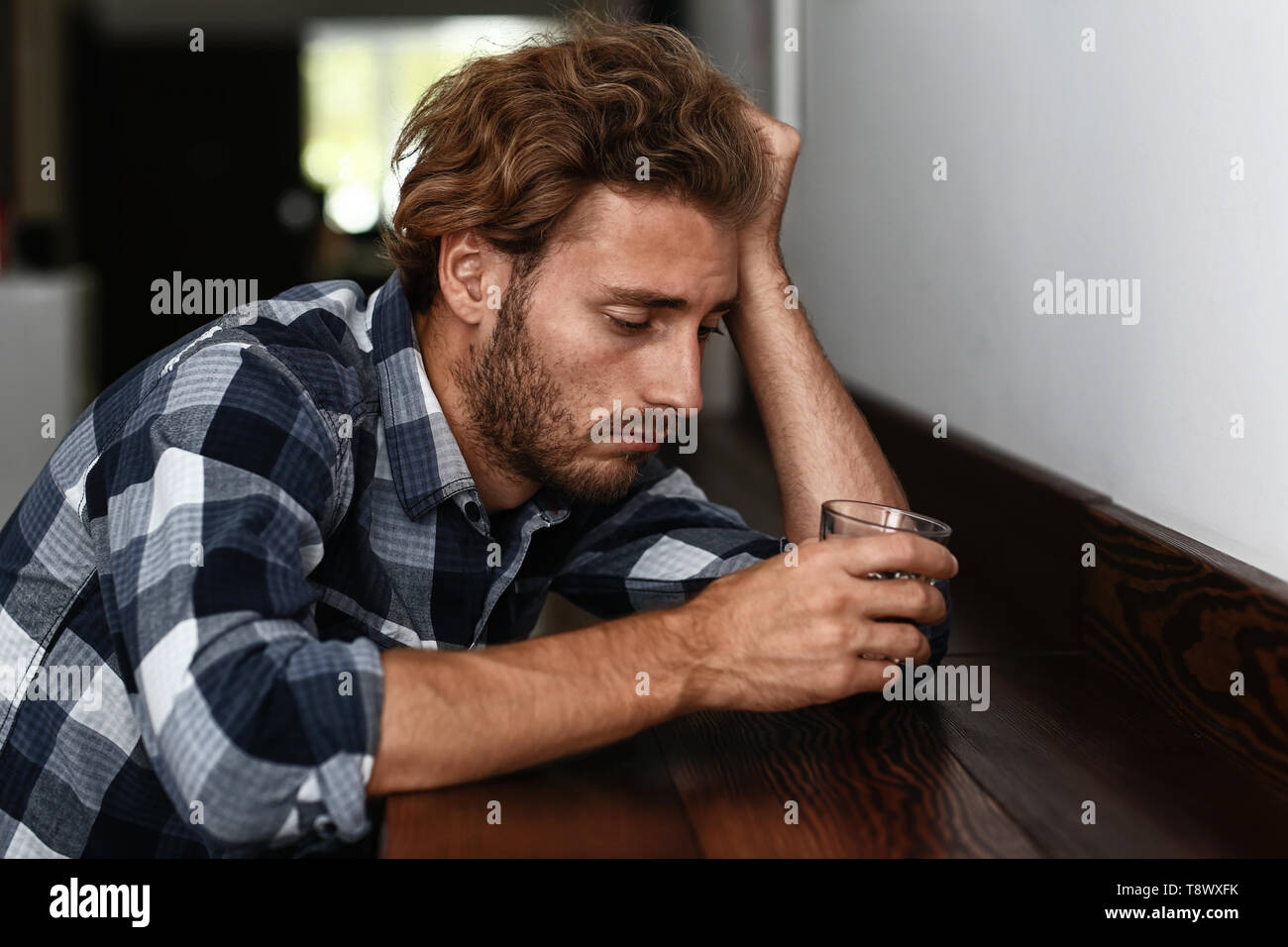 Depressed young man drinking alcohol in bar Stock Photo - Alamy