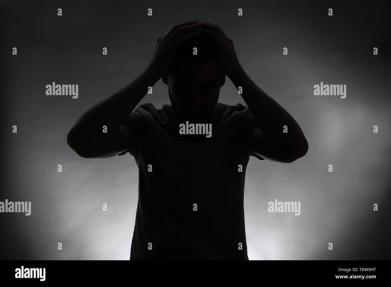 Silhouette of stressed man on dark background Stock Photo - Alamy