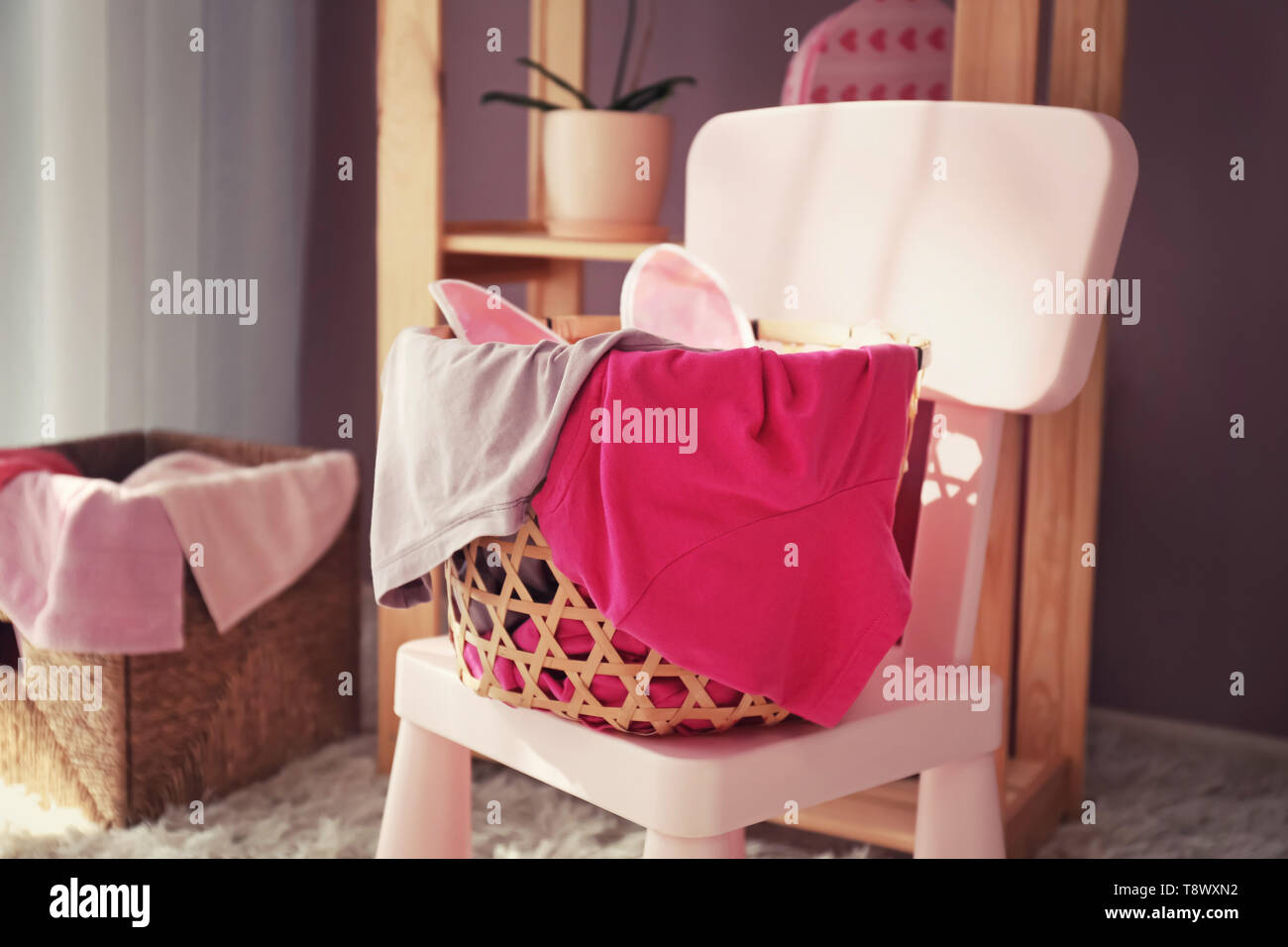 Laundry basket with dirty clothes on chair Stock Photo - Alamy