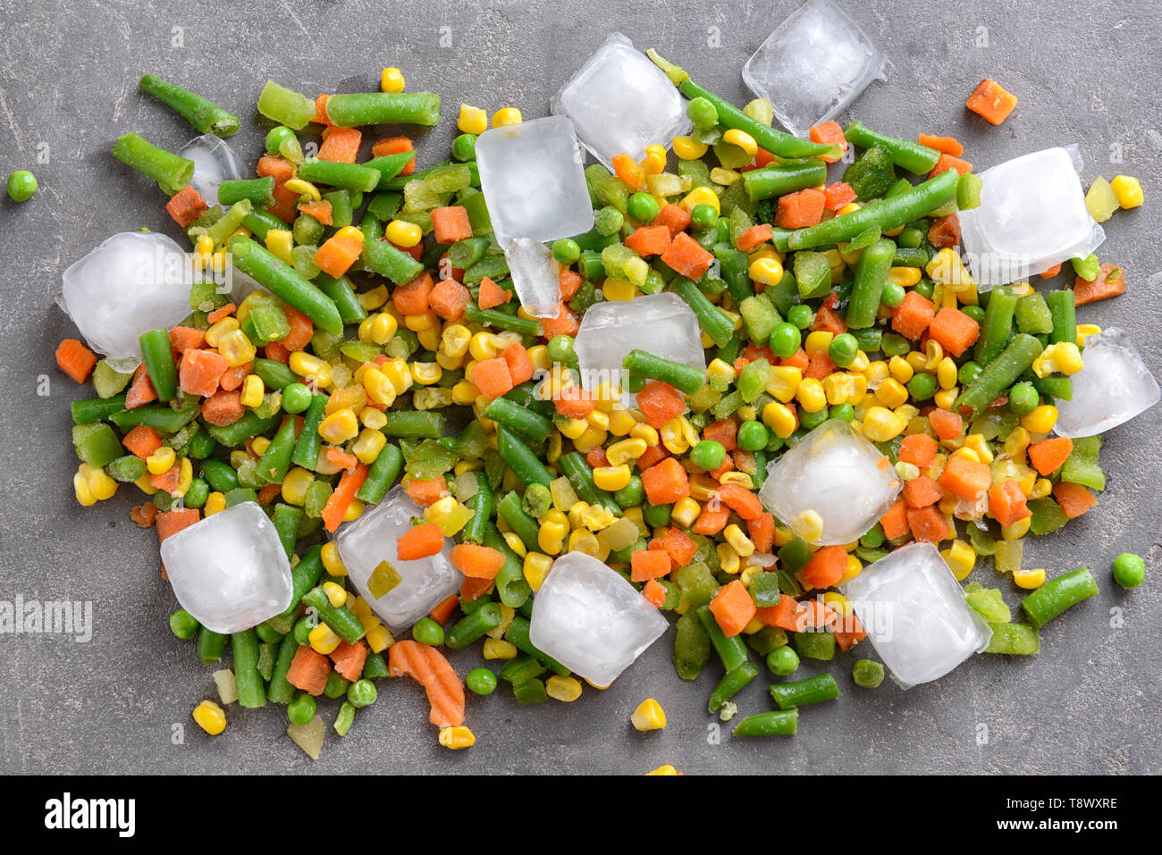 Frozen vegetables with ice cubes on grey background Stock Photo - Alamy
