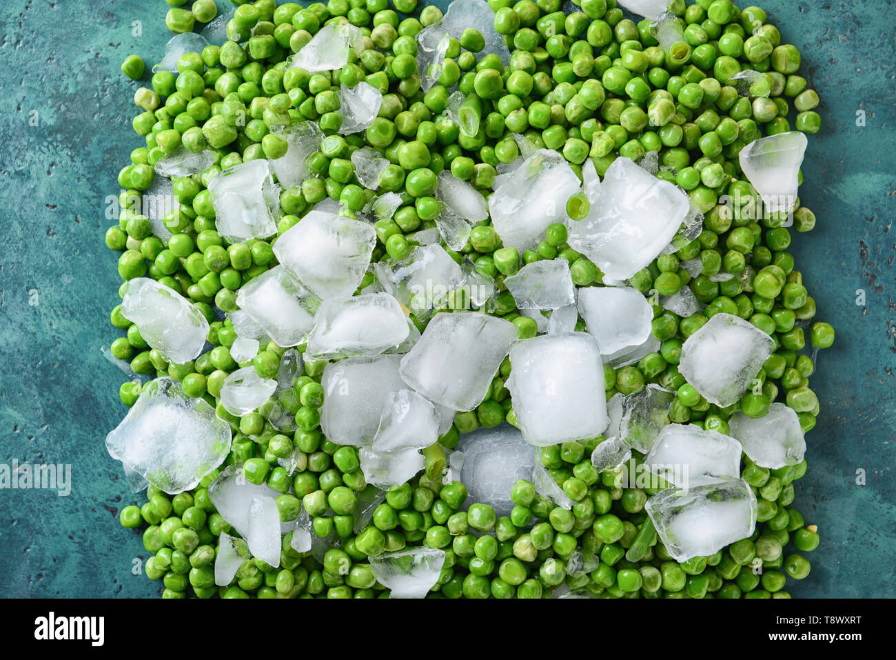 Frozen green peas with ice cubes on color background Stock Photo - Alamy