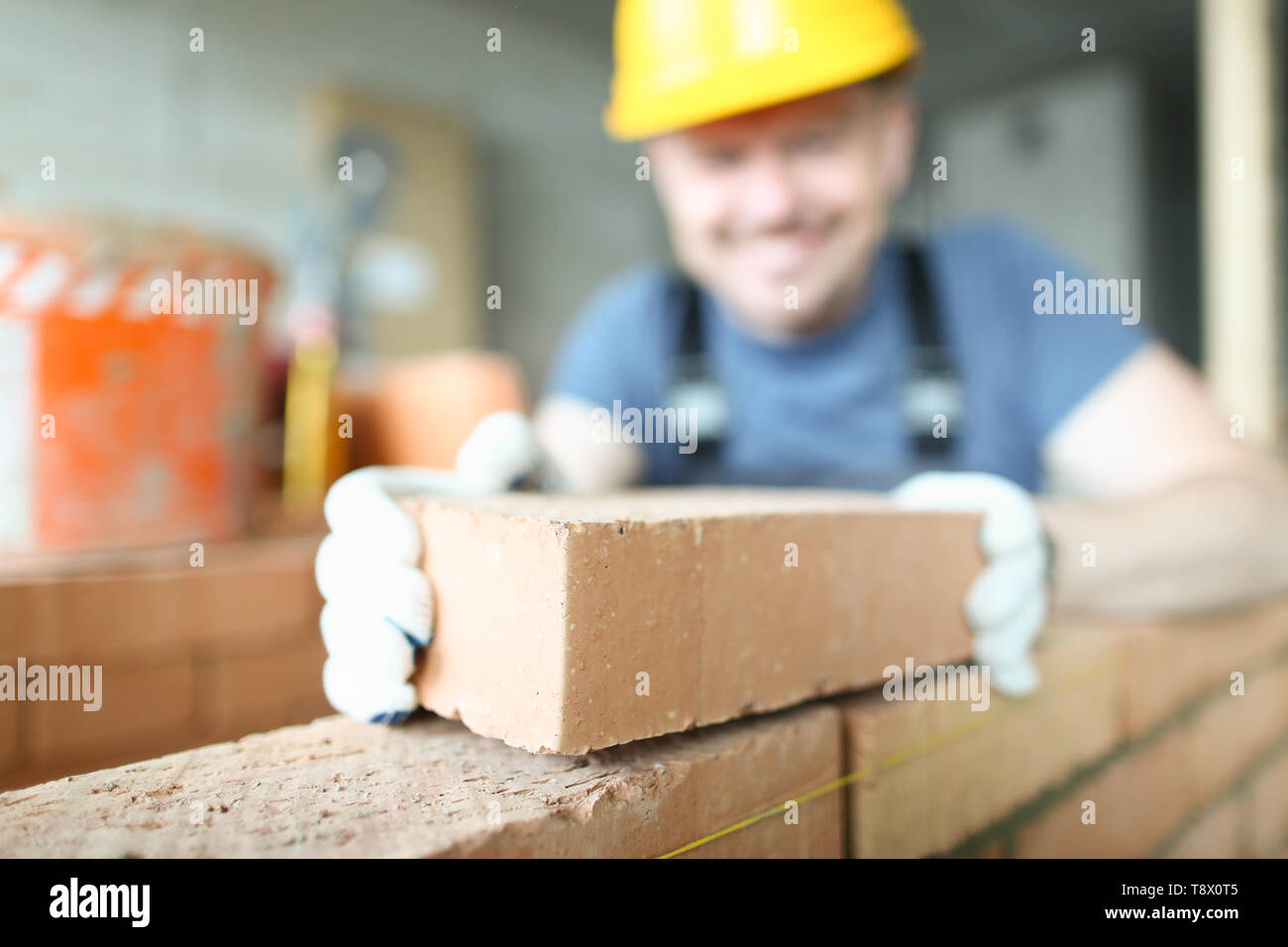 Male smiling builder puts make brickwork Stock Photo - Alamy