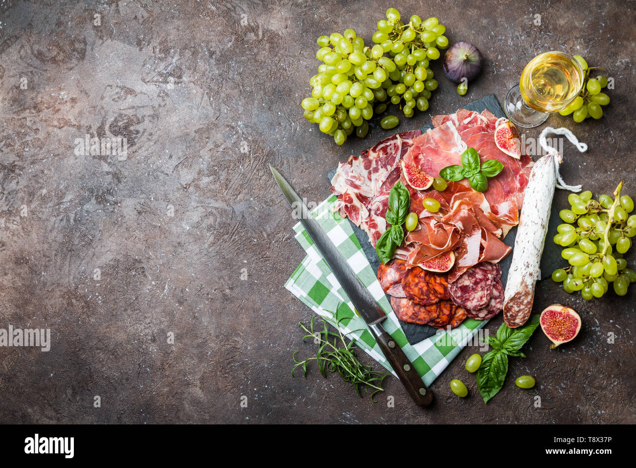 Sliced jamon on cutting board with figs, grapes and white wine. Parma ...