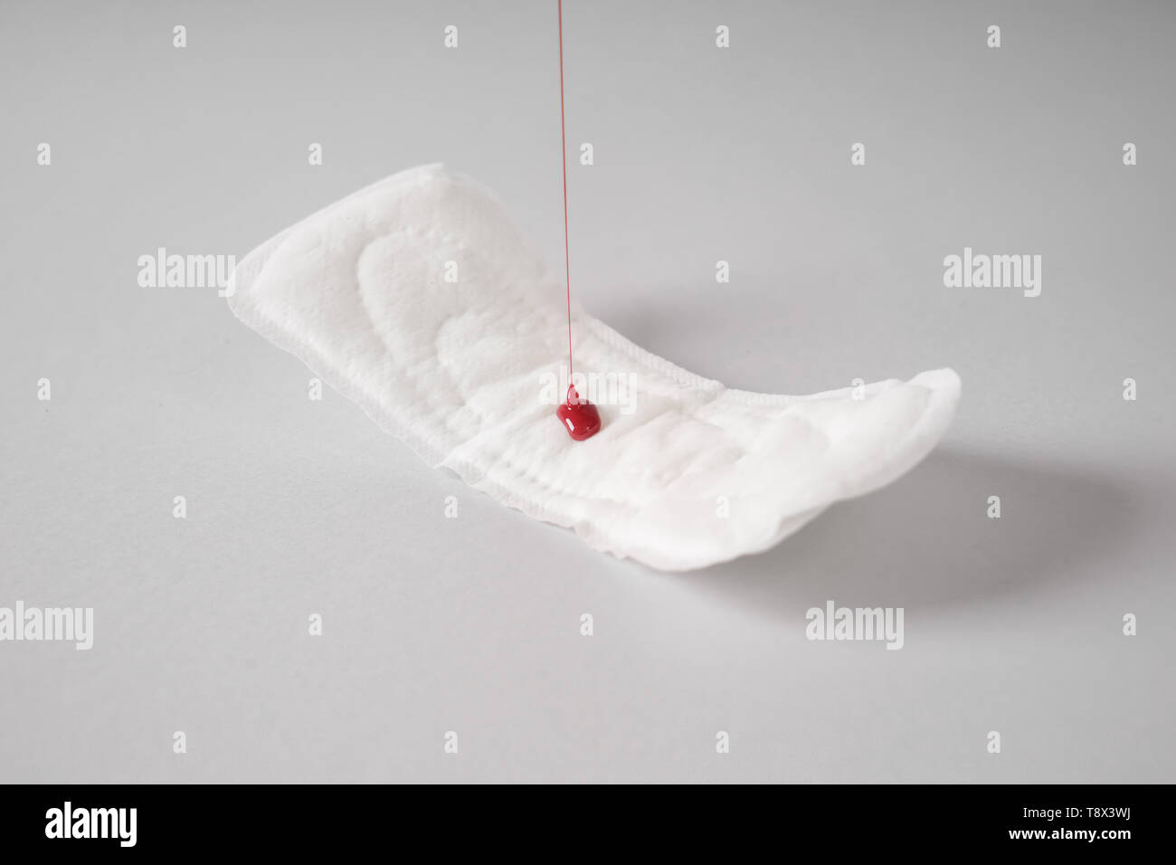 Pouring of red paint onto menstrual pad on grey background Stock Photo ...
