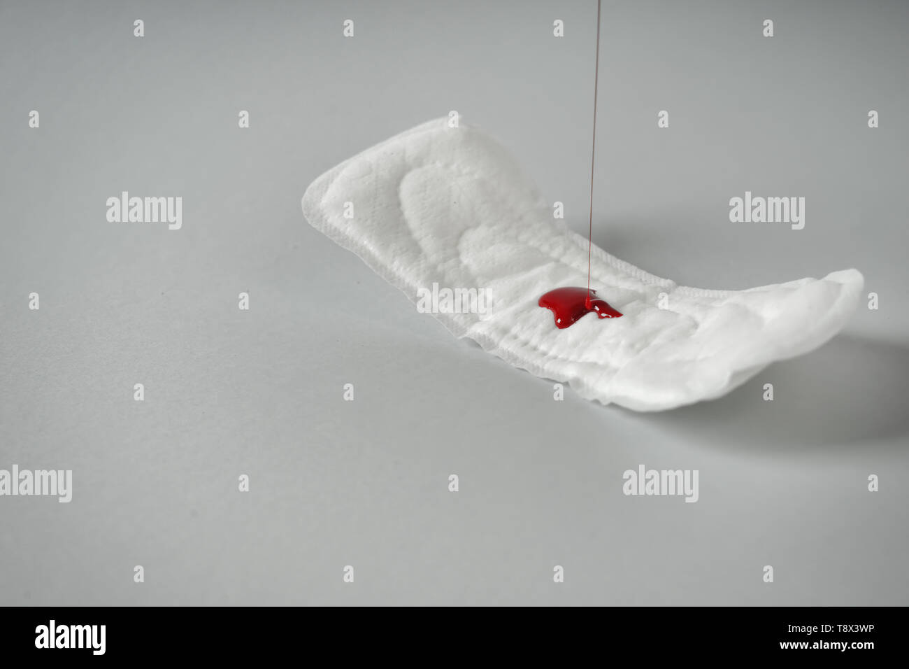 Pouring of red paint onto menstrual pad on grey background Stock Photo ...