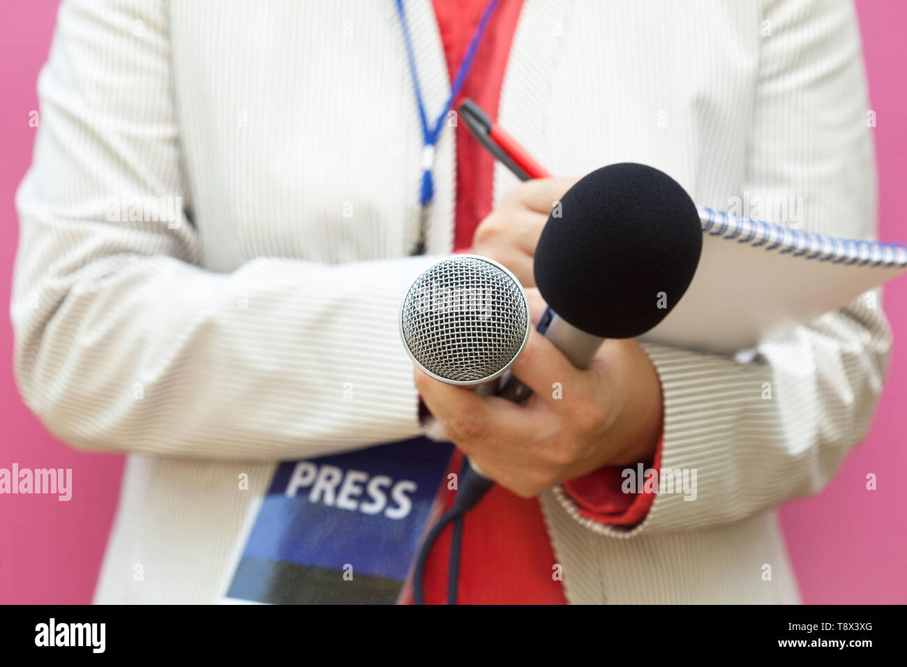 Female journalist at news conference, writing notes, holding microphone ...