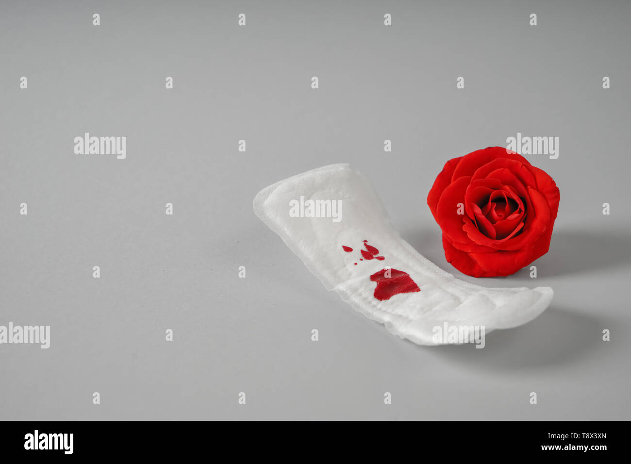 Menstrual pad with red stain and rose on grey background Stock Photo ...