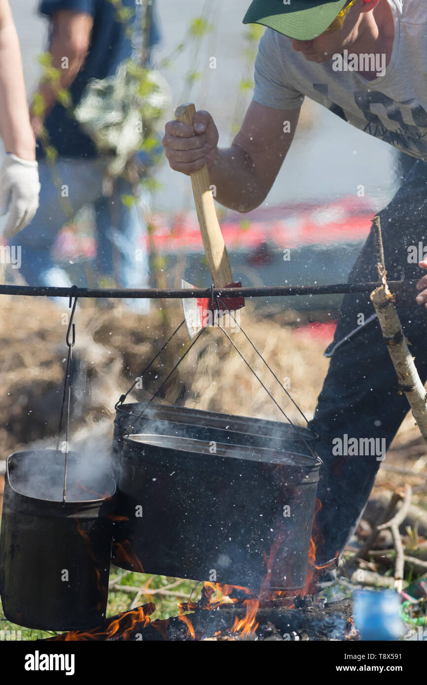 People heating up water in the metal buckets using a bonfire. A man ...