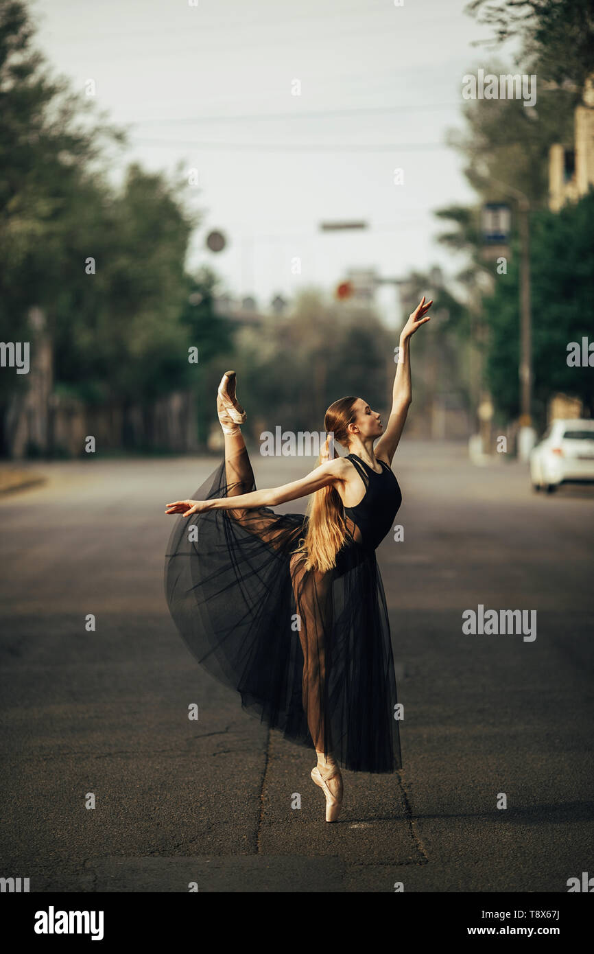 Ballerina standing in arabesque pose in a black transparent dress ...