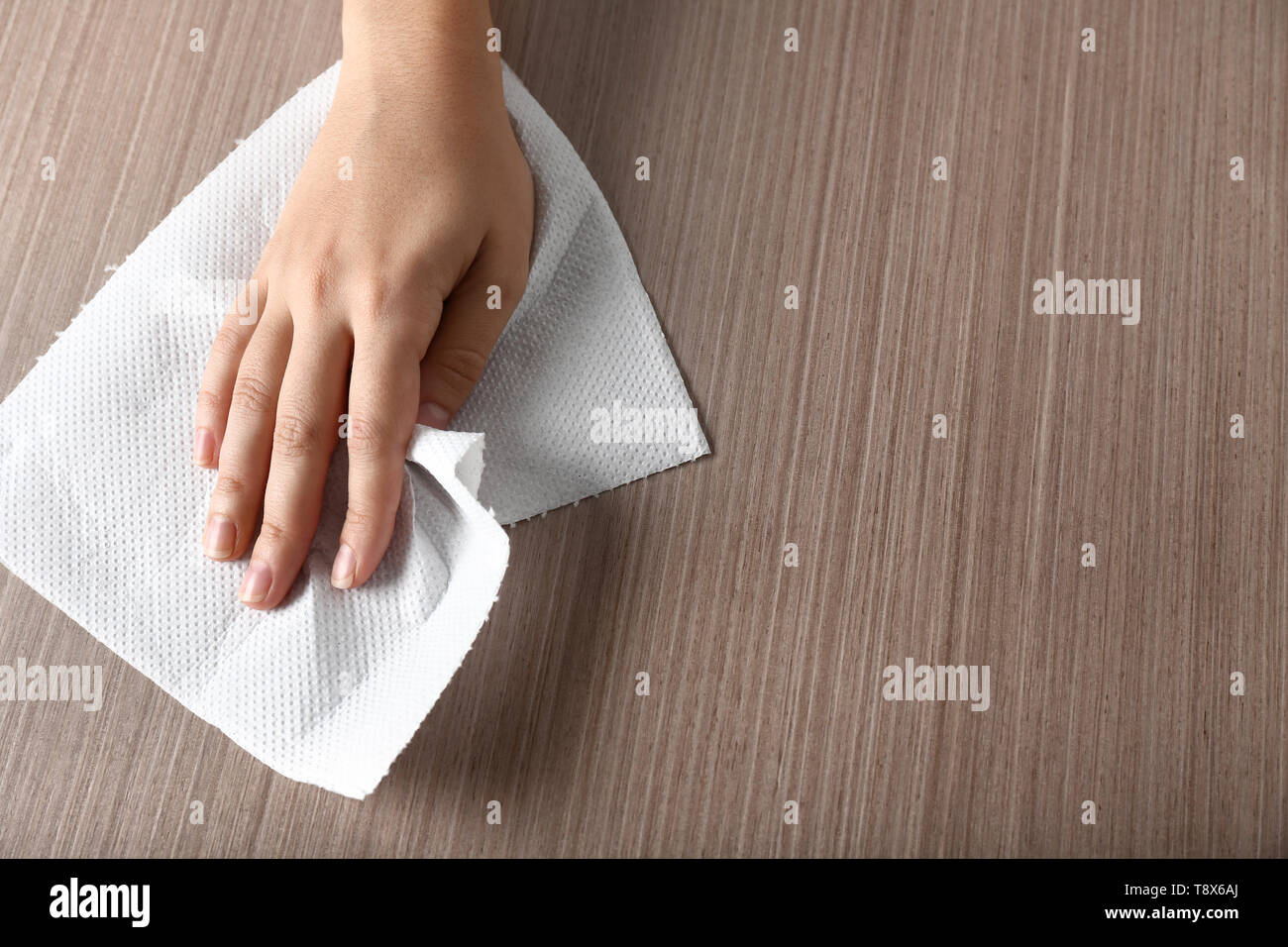 Woman wiping wooden table with paper towel Stock Photo - Alamy