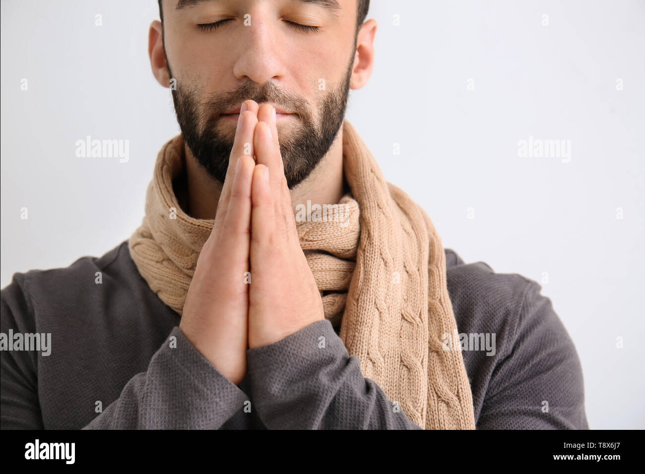 Religious young man praying to God on light background Stock Photo - Alamy