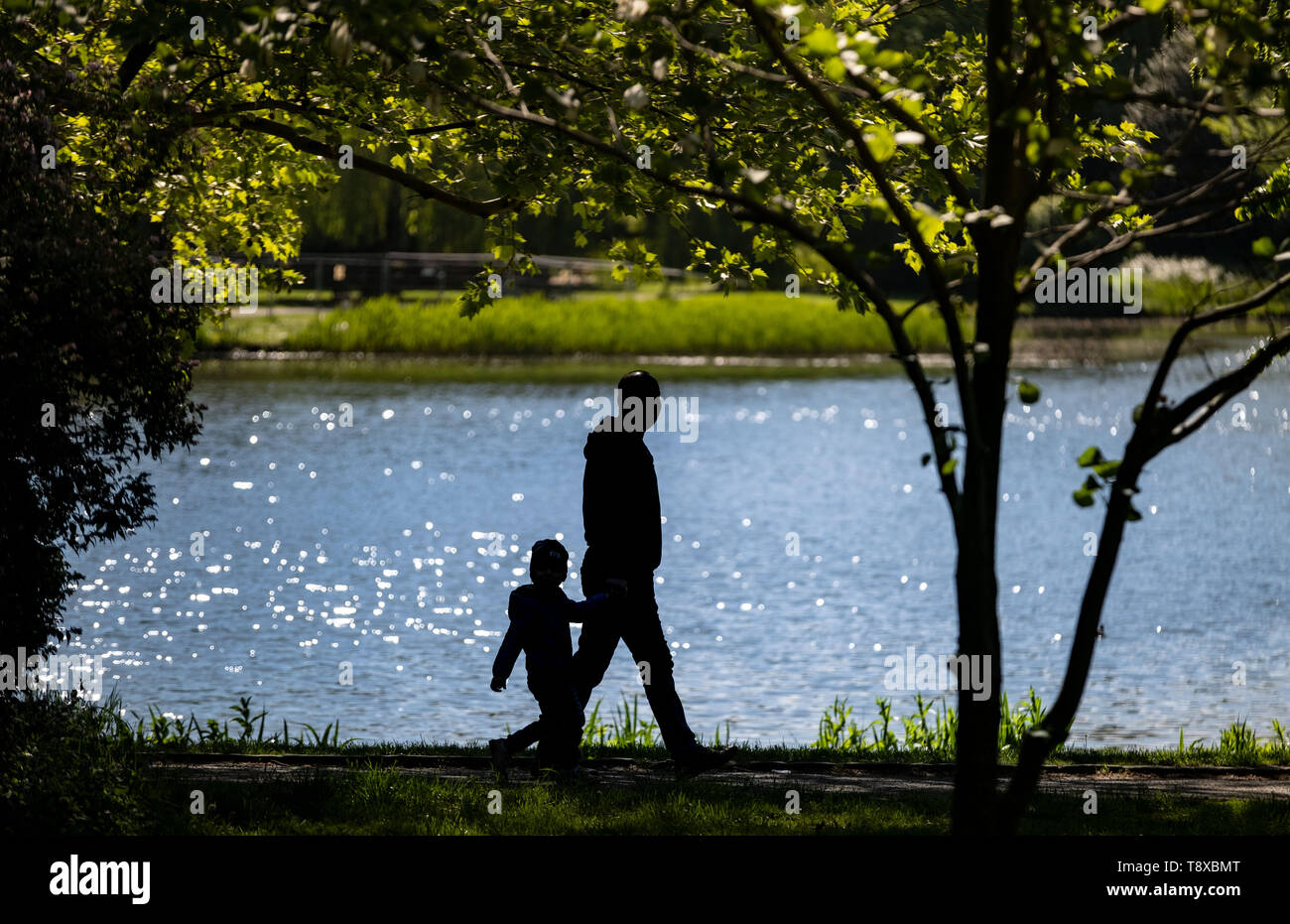 Hanover, Germany. 15th May, 2019. A man and a child walk in the shade ...