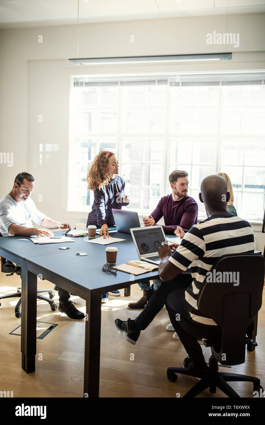 Group of diverse designers sitting around a boardroom table in an ...