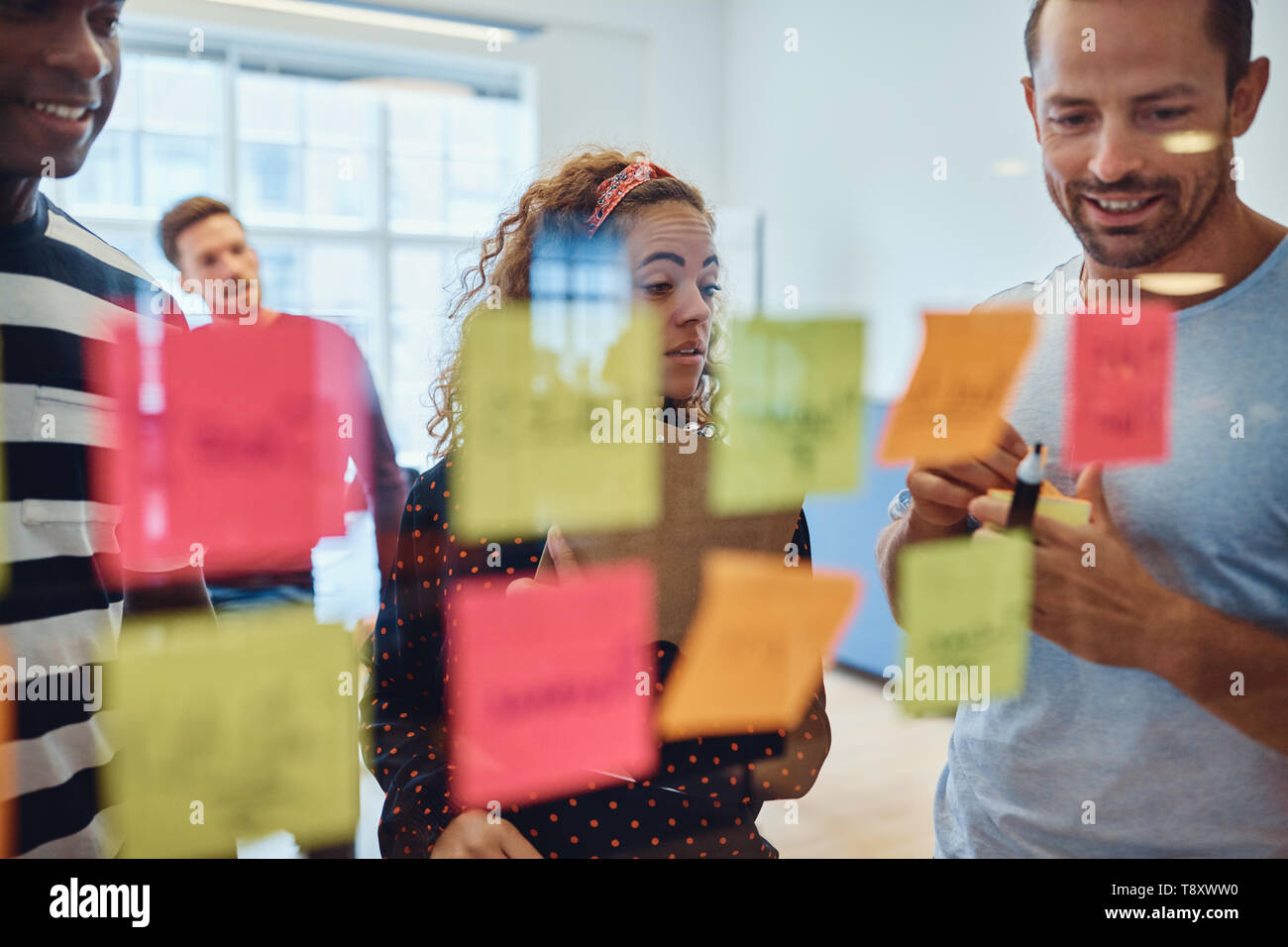 Group of diverse designers standing in an office brainstorming with ...