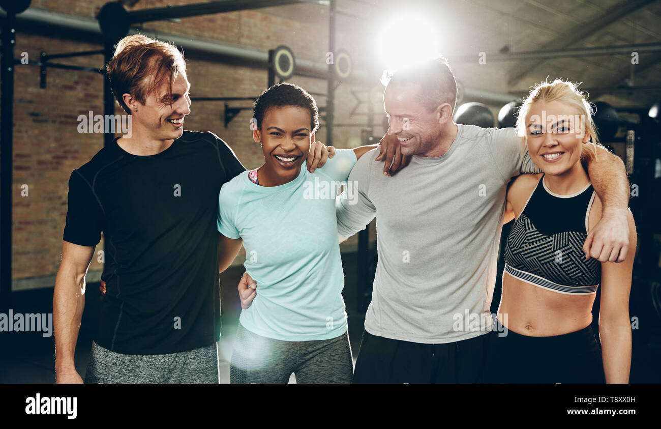 Laughing group of diverse friends in sportswear standing arm in arm at ...