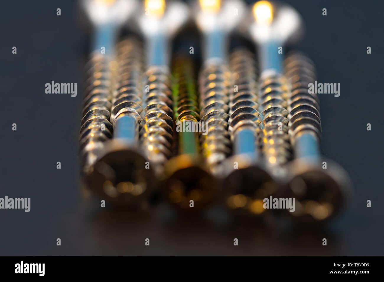 golden screw in the middle of silver screws, diy background Stock Photo ...