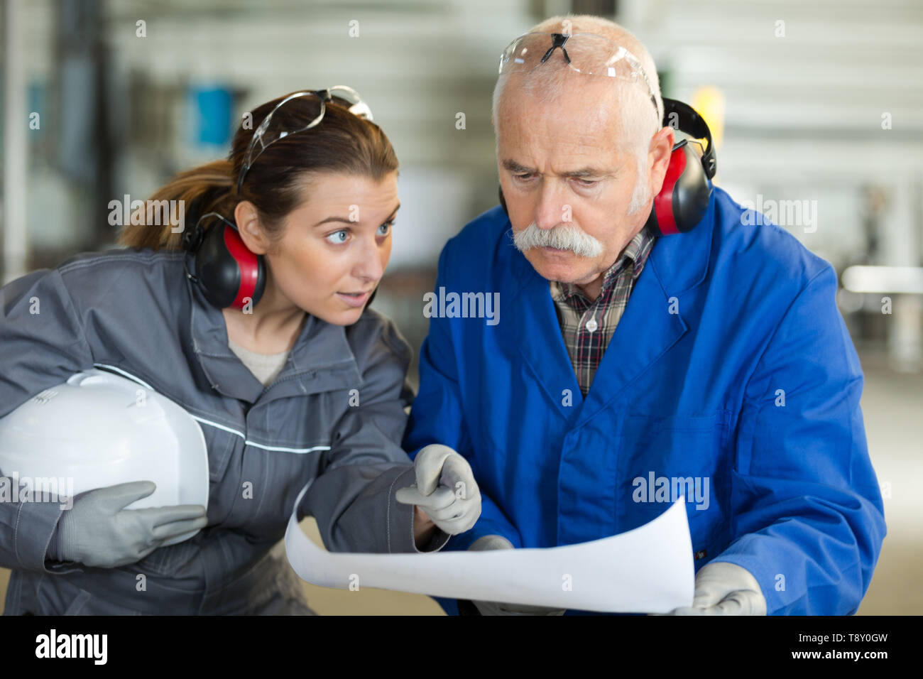 female manual worker asking question to supervisor holding paperwork ...