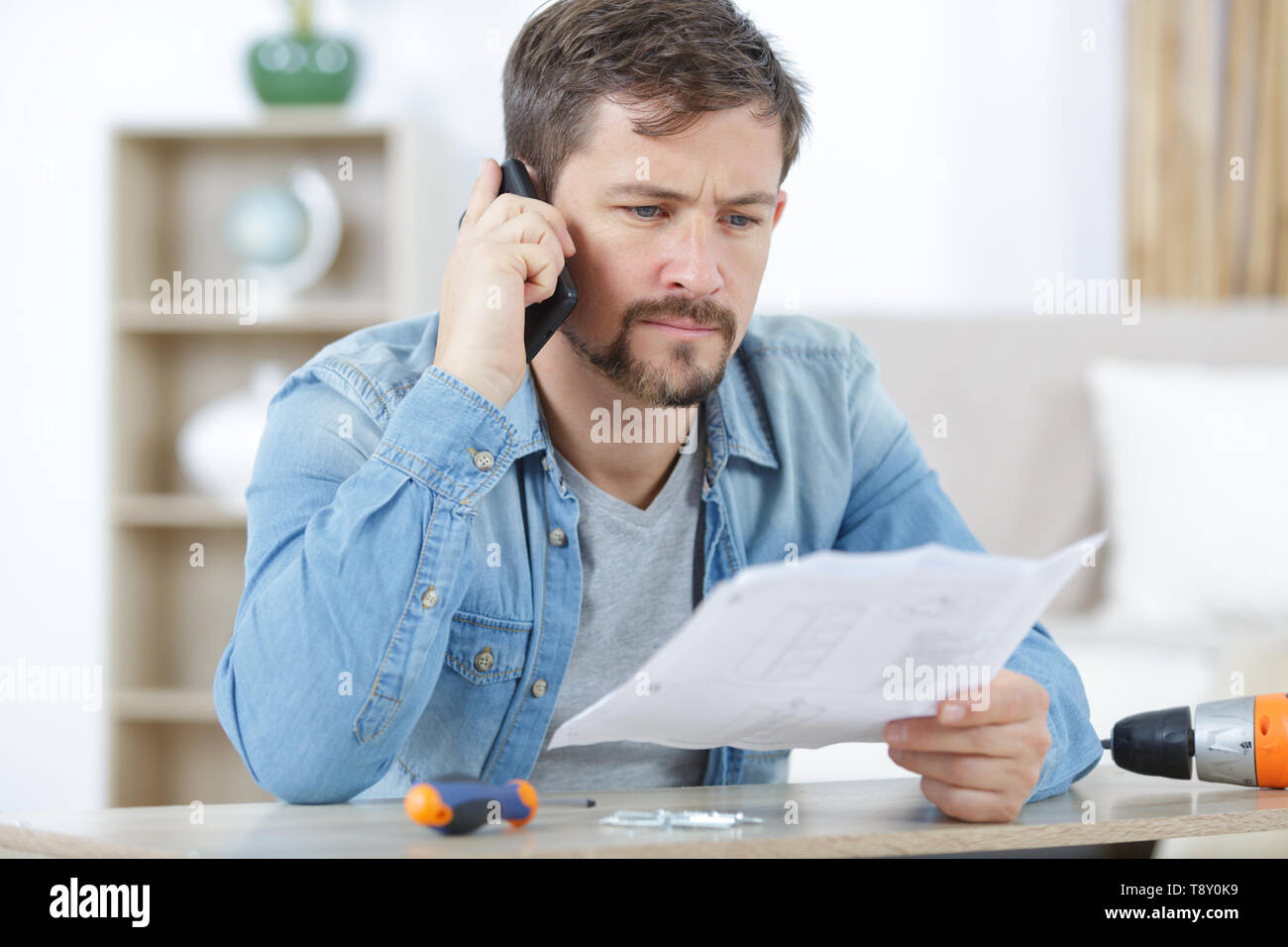 repair contractor on the phone repairing broken furniture at home Stock ...