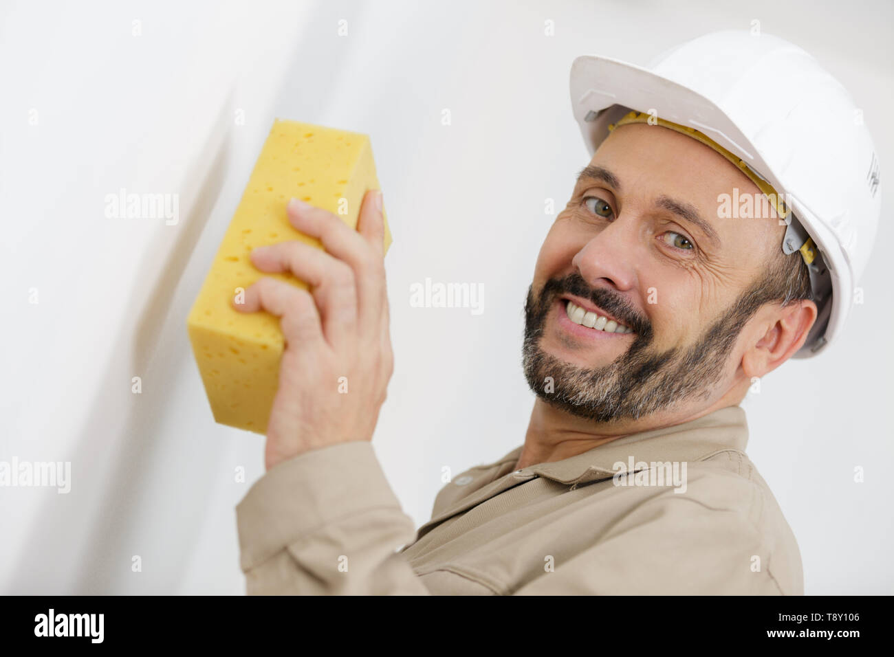 happy male builder washing a wall after plastering Stock Photo - Alamy