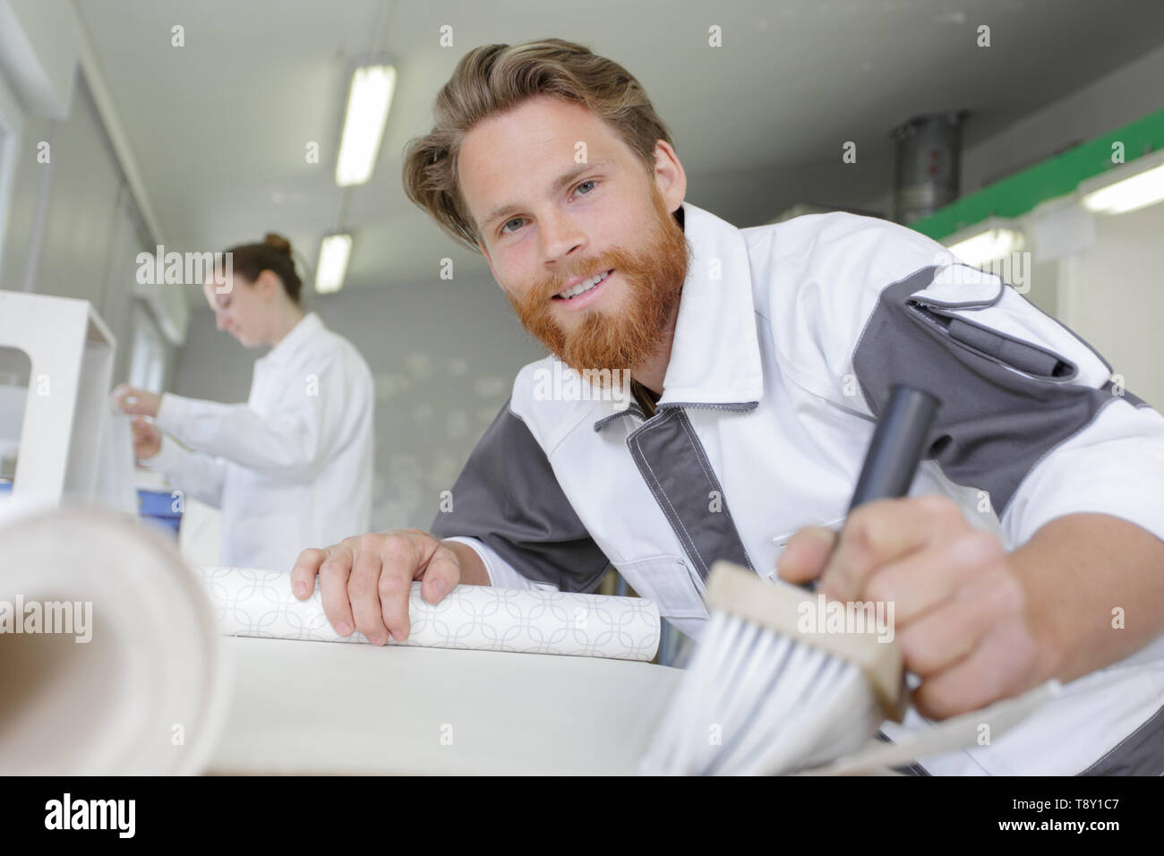 man smears glue with a brush to lay wall paper Stock Photo - Alamy