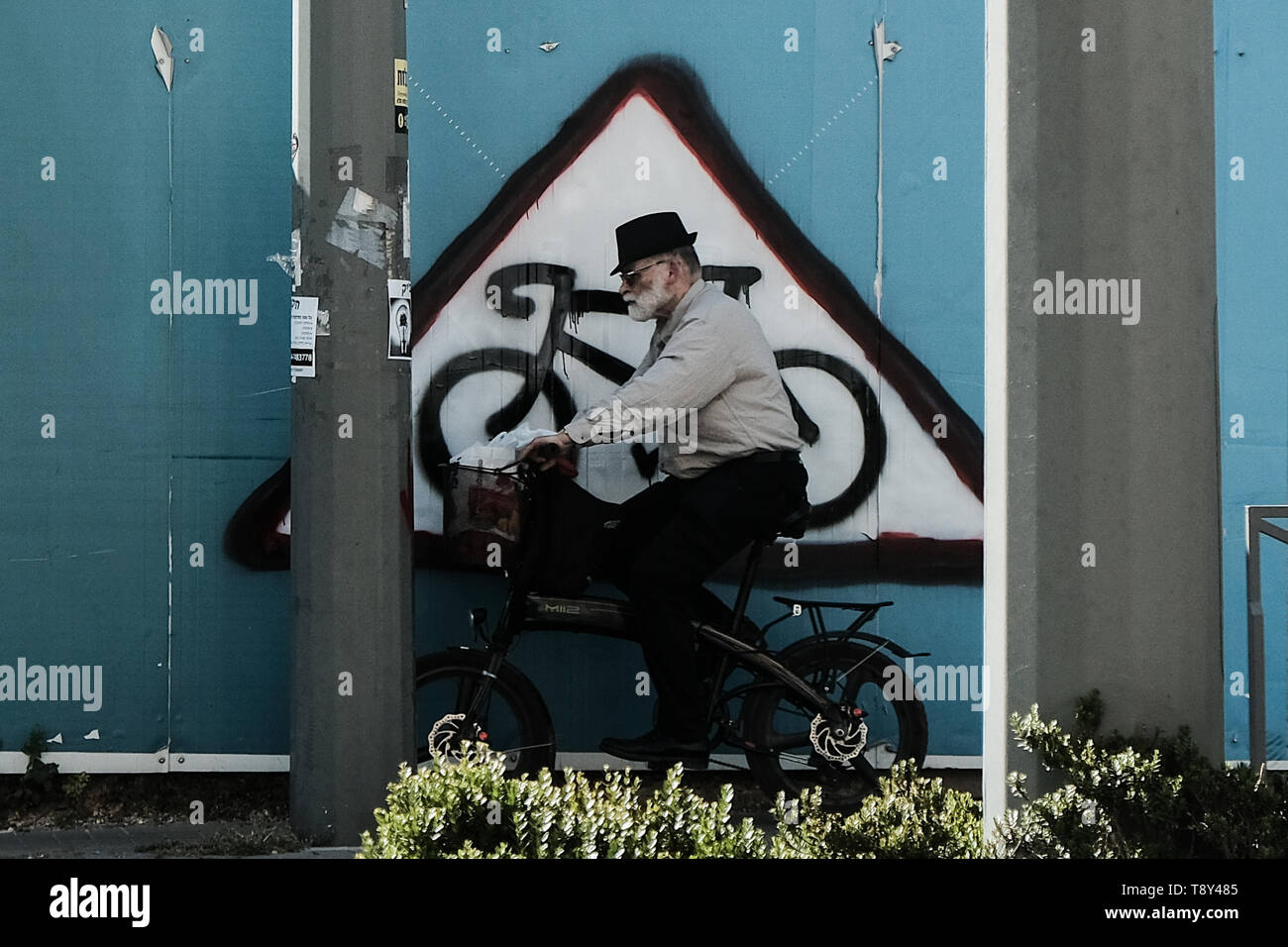 A man rides a bicycle past graffiti depicting a bicycle in the ...