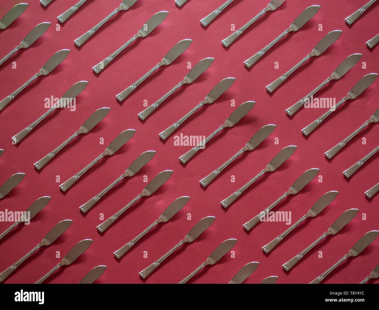 Silver spread knives pattern on red background Stock Photo - Alamy