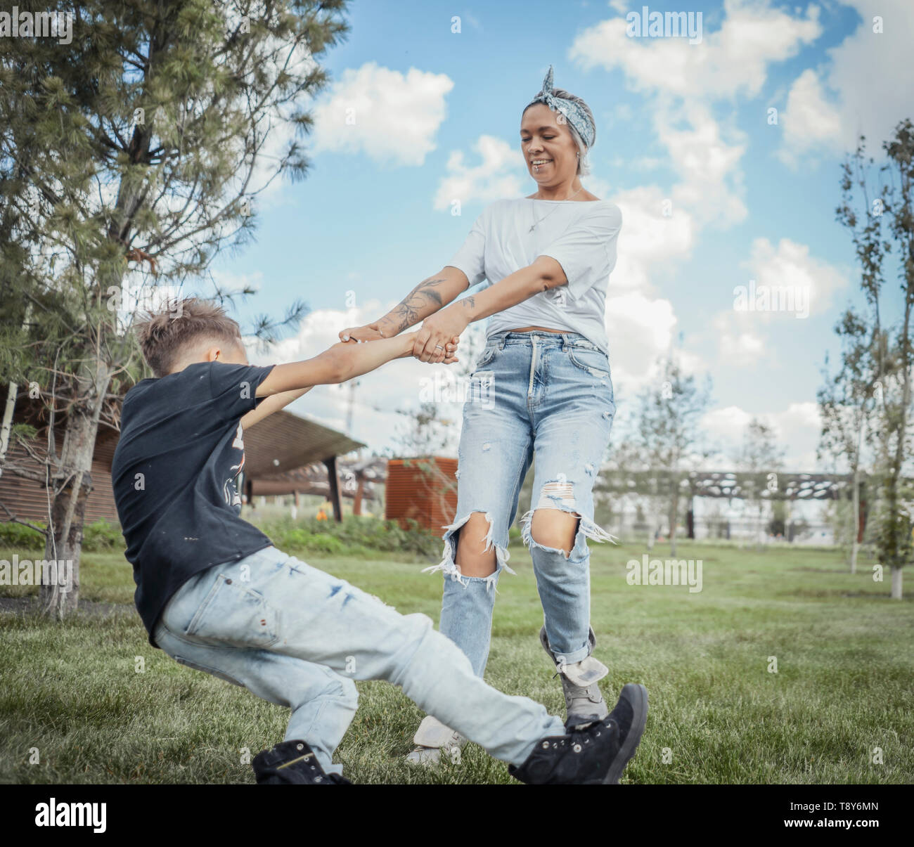 Pretty mum turning around, whirling with her son at park. Happy family ...