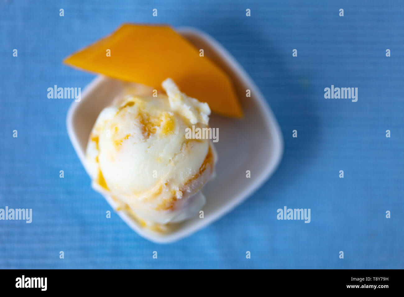 Fresh scoop of yoghurt ice cream with mango variegato and fresh mango ...
