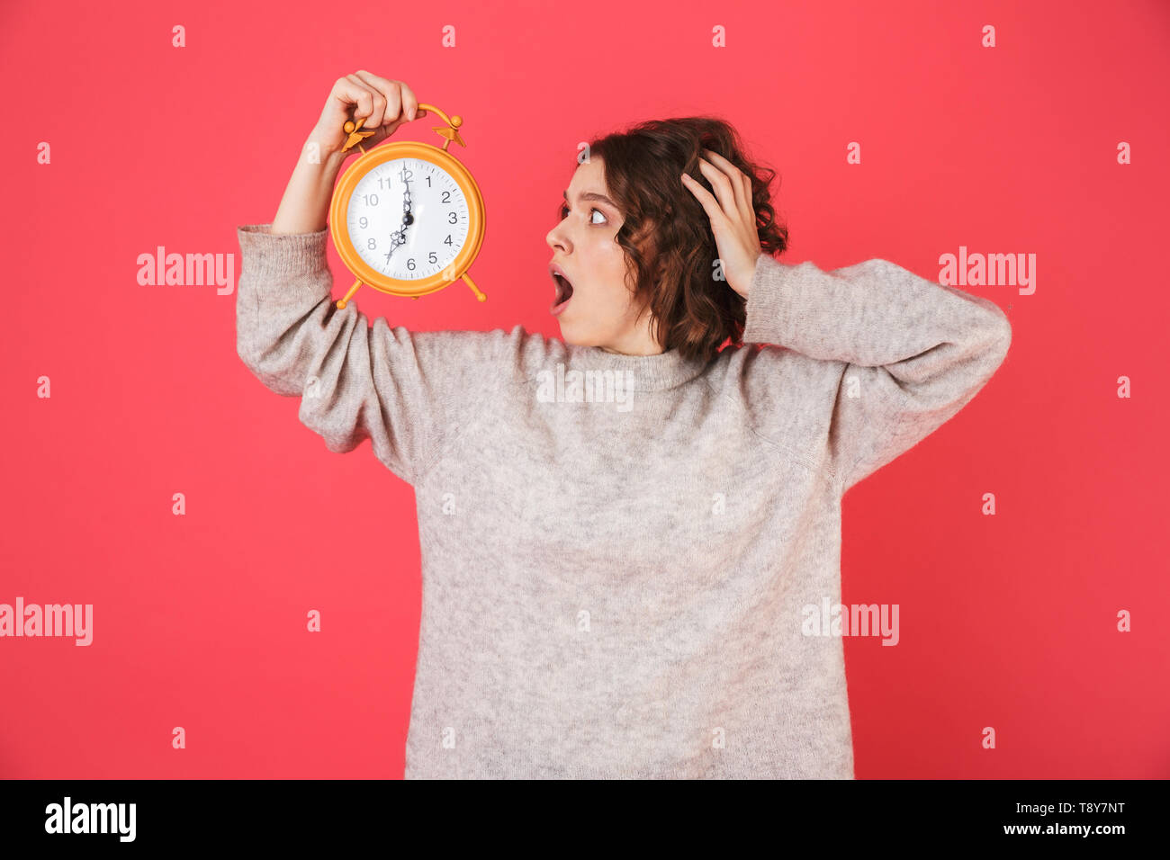 Portrait of a shocked young woman standing isolated over pink ...
