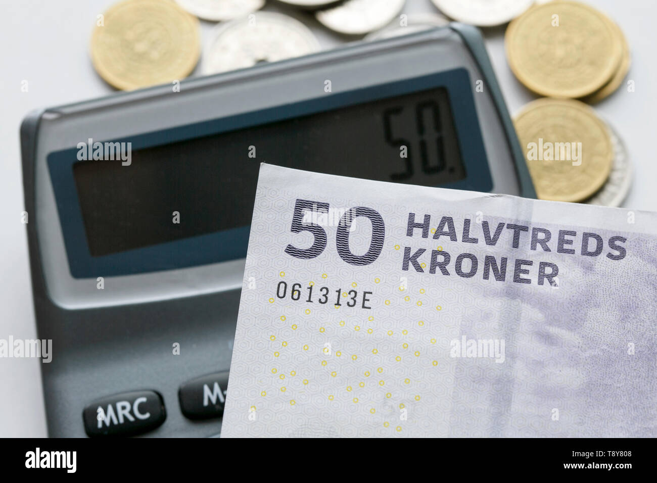 A fifty krone note over a calculator and mixed coins with selective ...