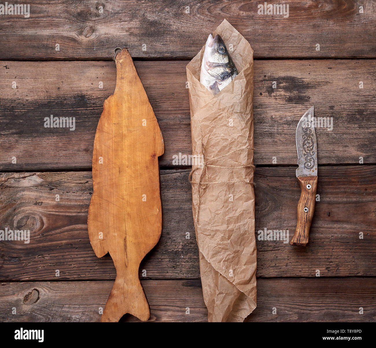 Fresh whole sea bass fish wrapped in a brown paper and tied with a rope ...