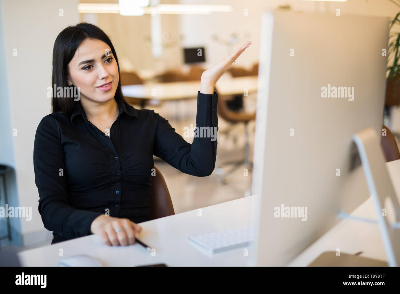 Young pretty woman with raised hands in front of screen pc sitting in ...