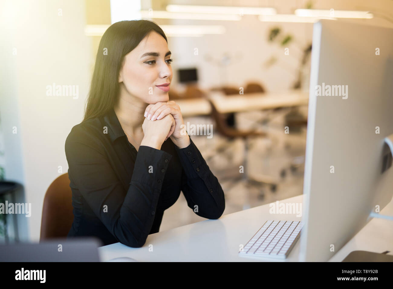 Office girl working on laptop computer at desk, looking at monitor ...