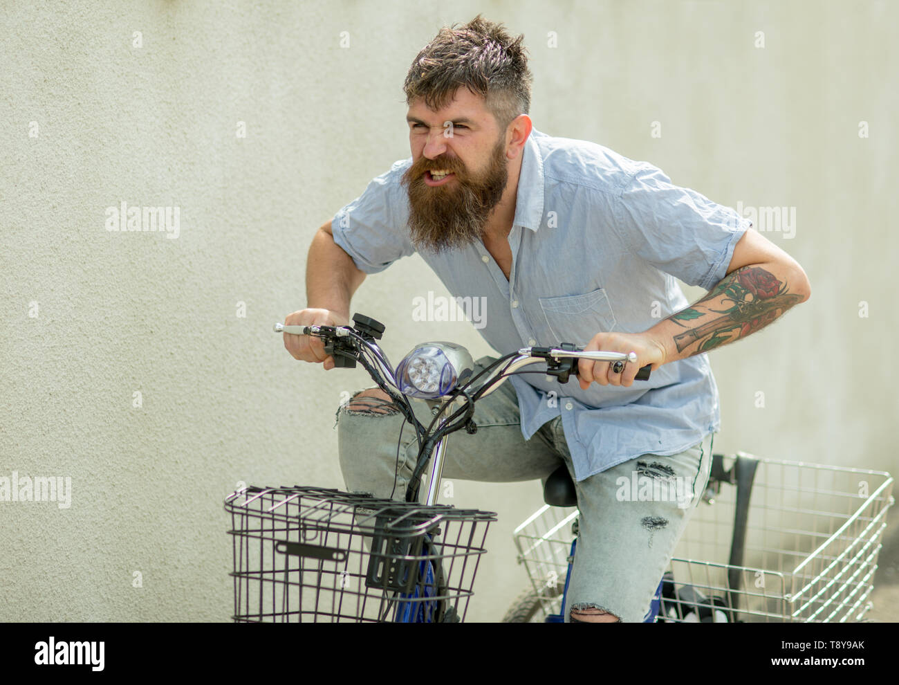 Hipster with tattooed arms ride bicycle. Bearded man travel by bike ...