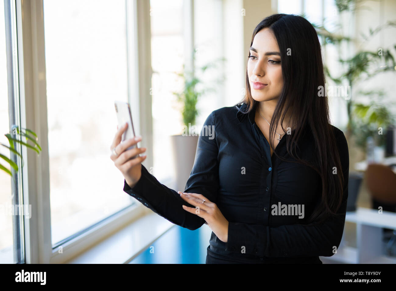 Portrait of happy lady typing in mobile while locating at desk in ...