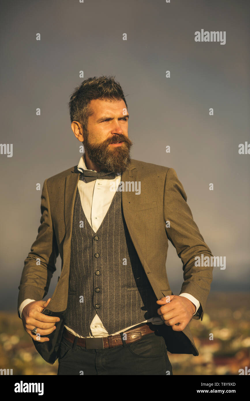Man with beard and mustache on cloudy sky. Man hiking in classic coat ...