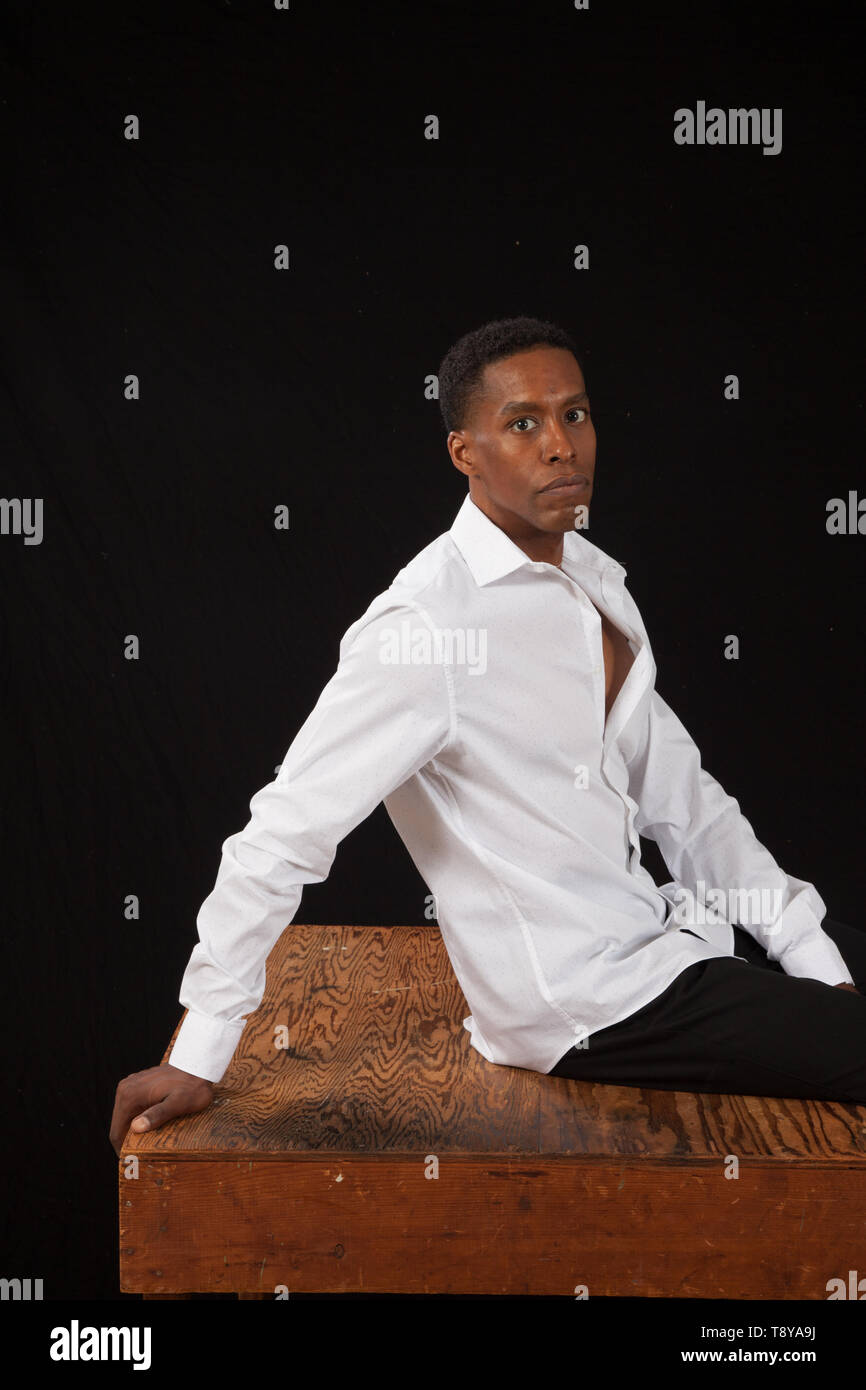 Handsome Black man sitting on a wood table Stock Photo - Alamy