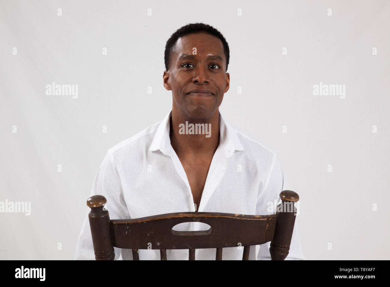 Handsome black man sitting backwards in a chair Stock Photo - Alamy