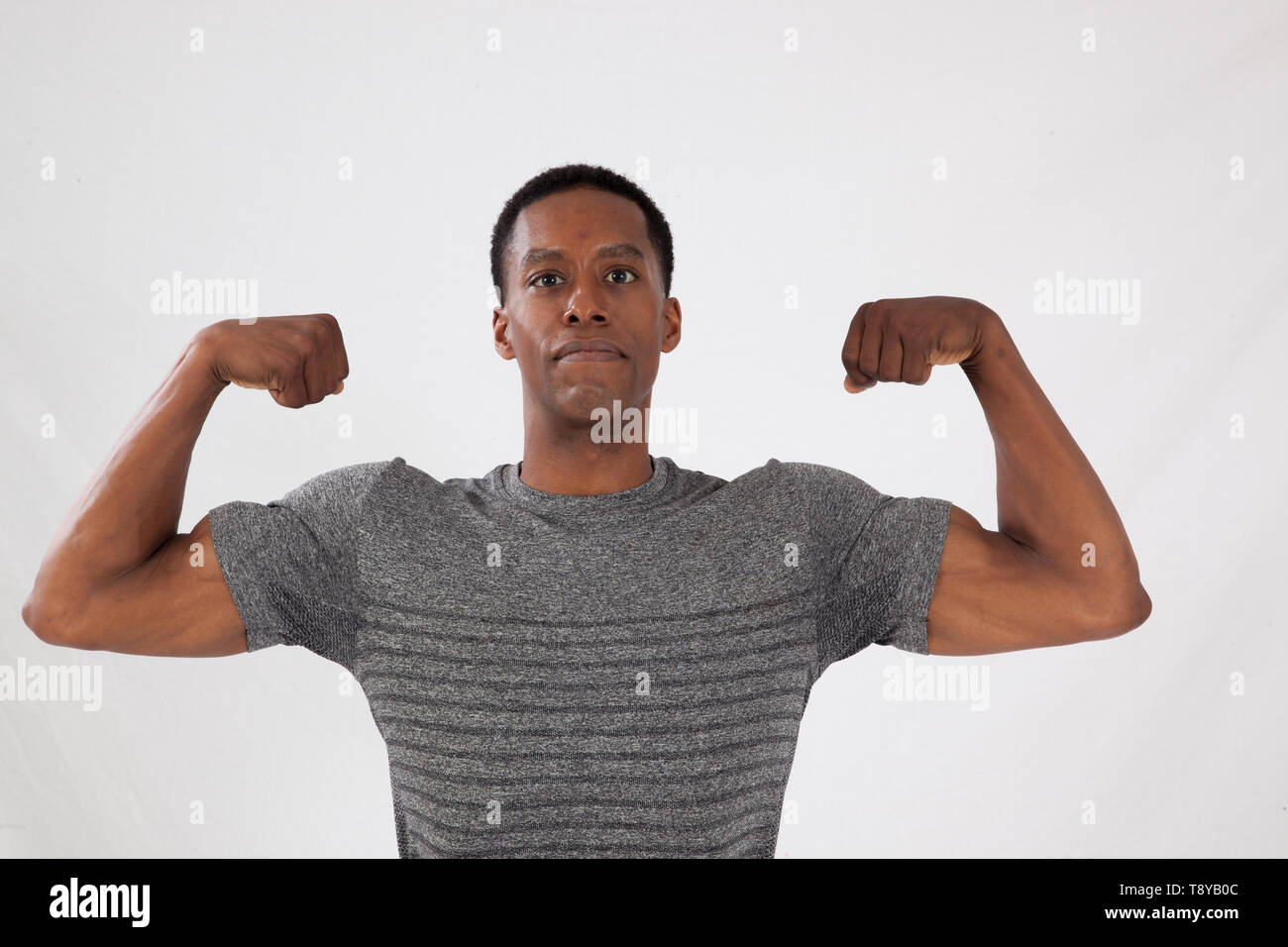 Handsome Black man in grey shirt, flexing his arm muscles Stock Photo ...