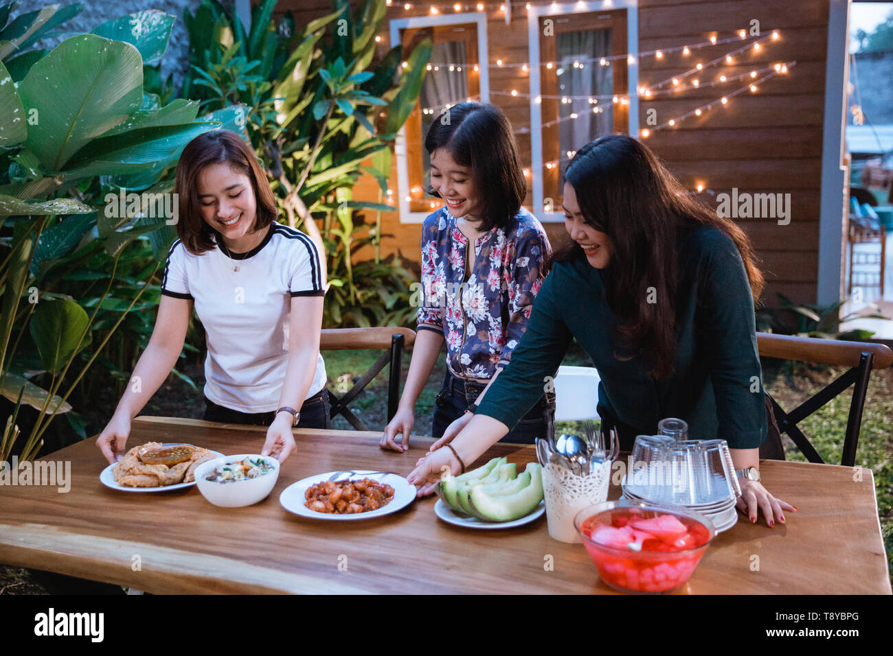 three woman preparing table for dinner at backyard Stock Photo - Alamy